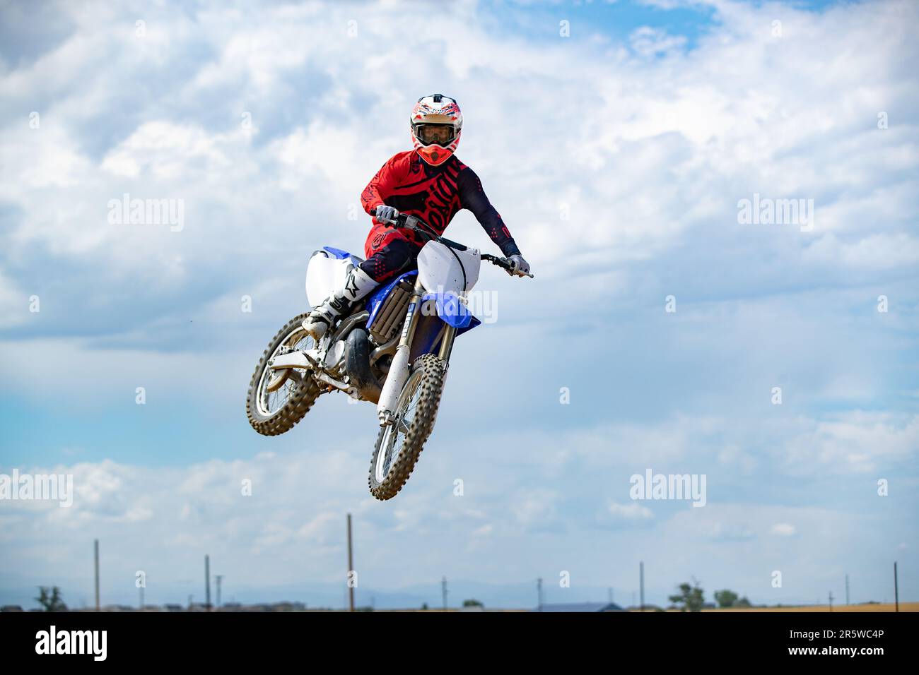 A Caucasian male performing a stunt jump on a dirt bike in mid-air ...