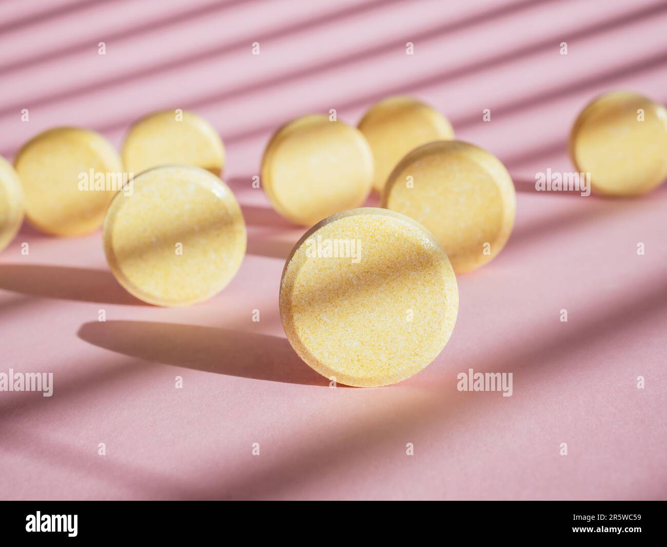 Heap of soluble effervescent vitamin tablets on a pink paper background ...