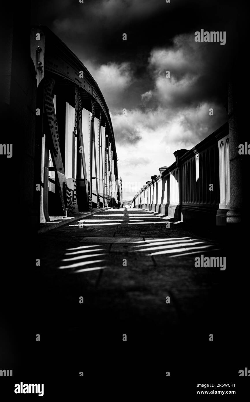A vertical of a metallic bridge on a cloudy day in grayscale Stock ...