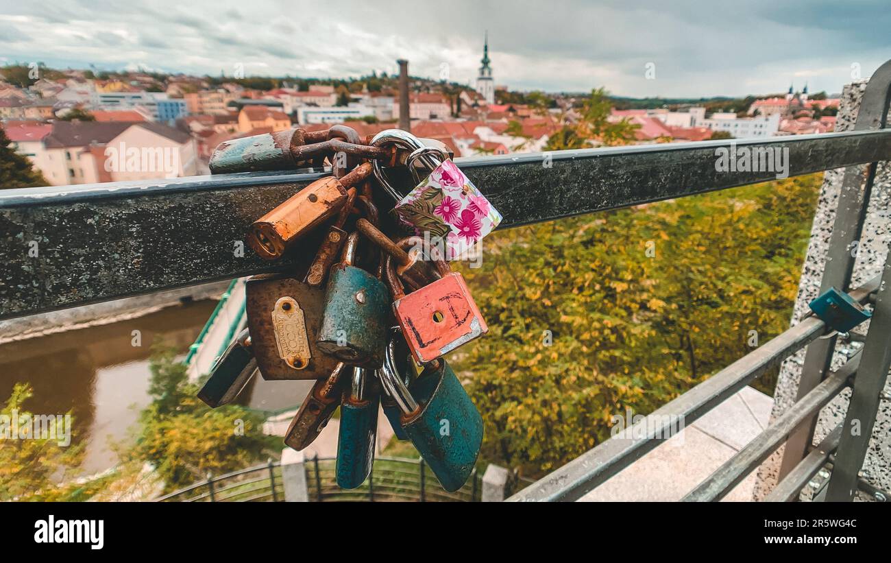 A set of small padlocks fixed to a metal railing in a variety of colors ...