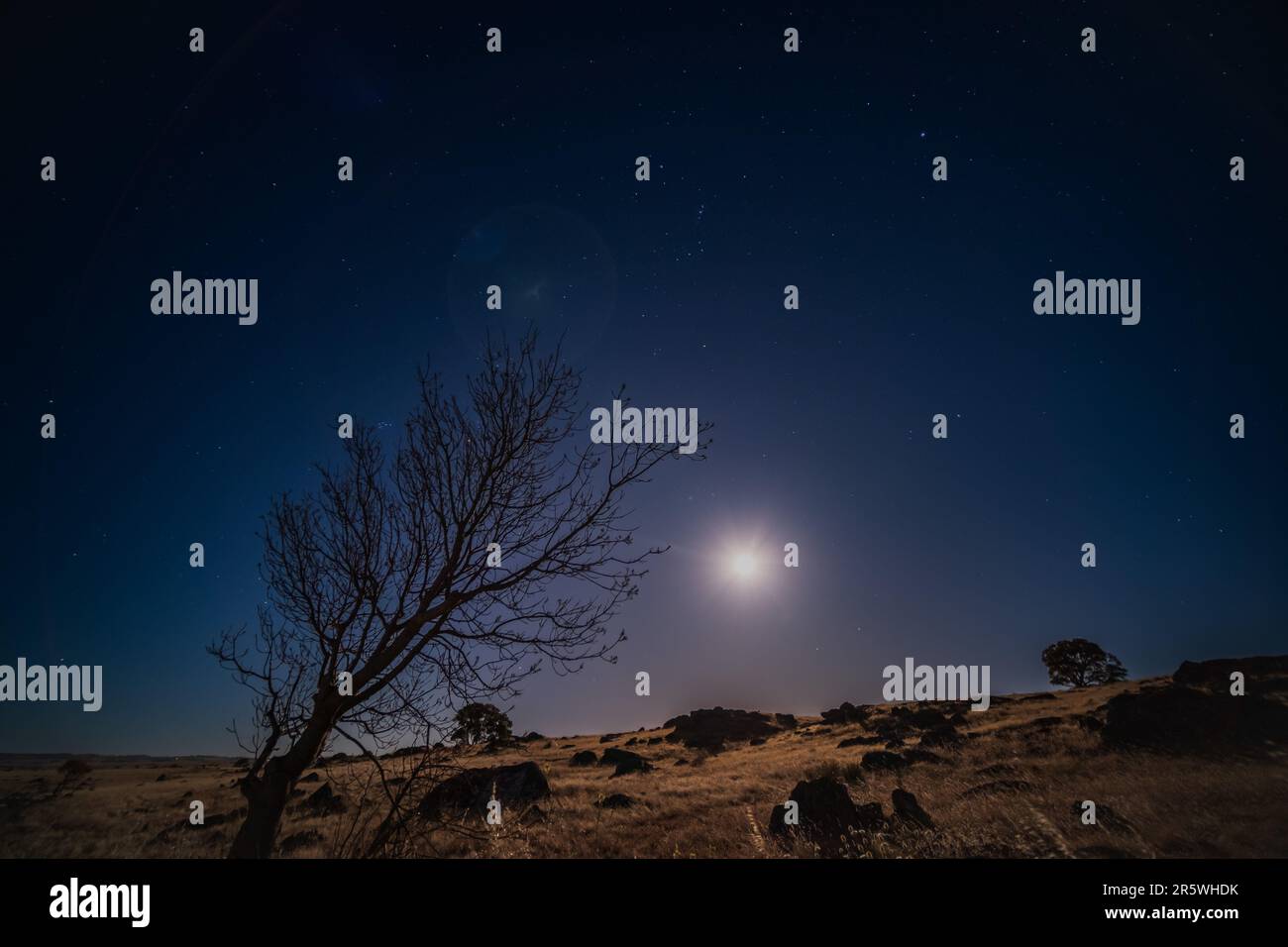 A stunning landscape featuring a full moon setting above a vast open ...