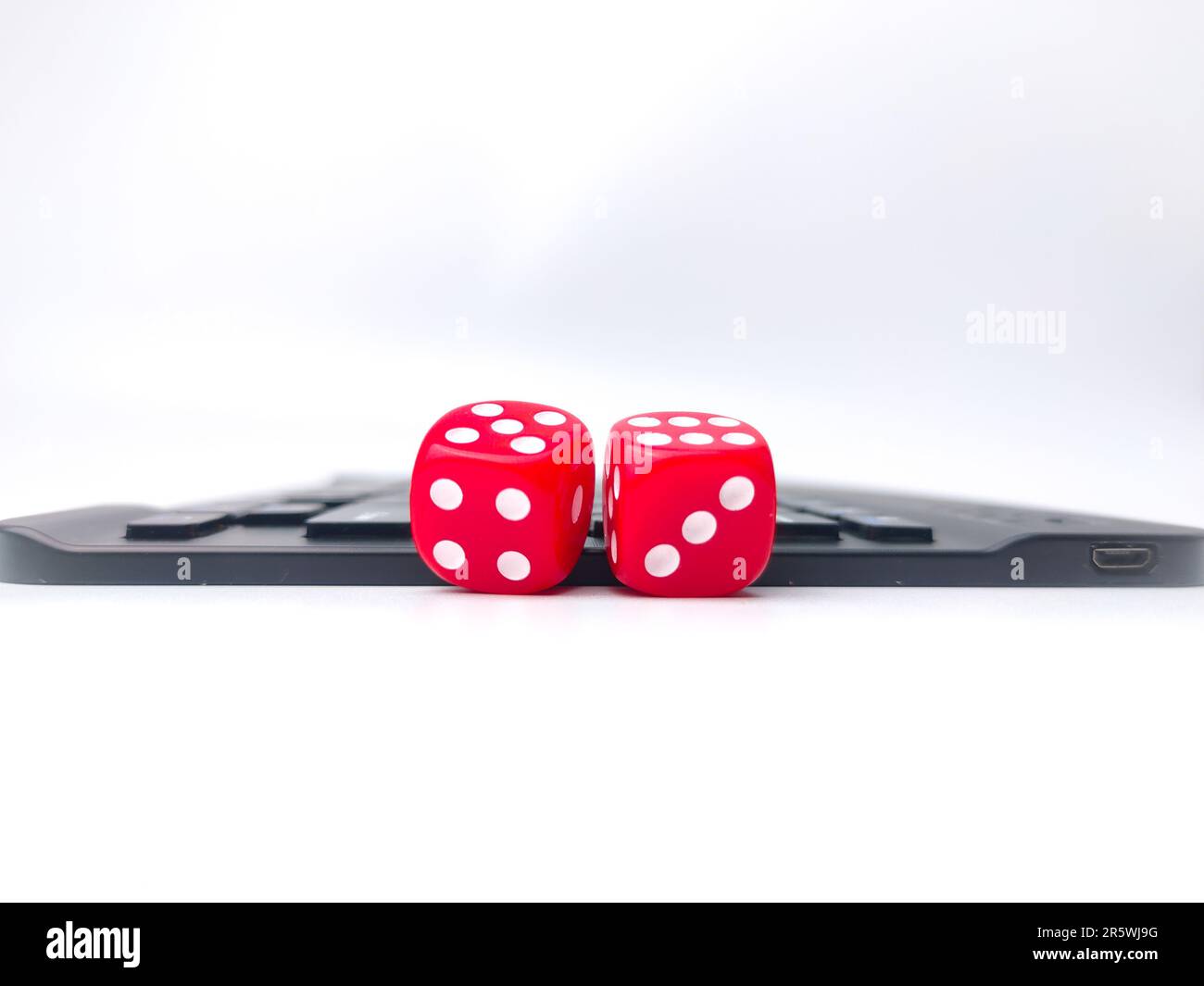 Two red dice cubes on top of a black computer keyboard against a white ...