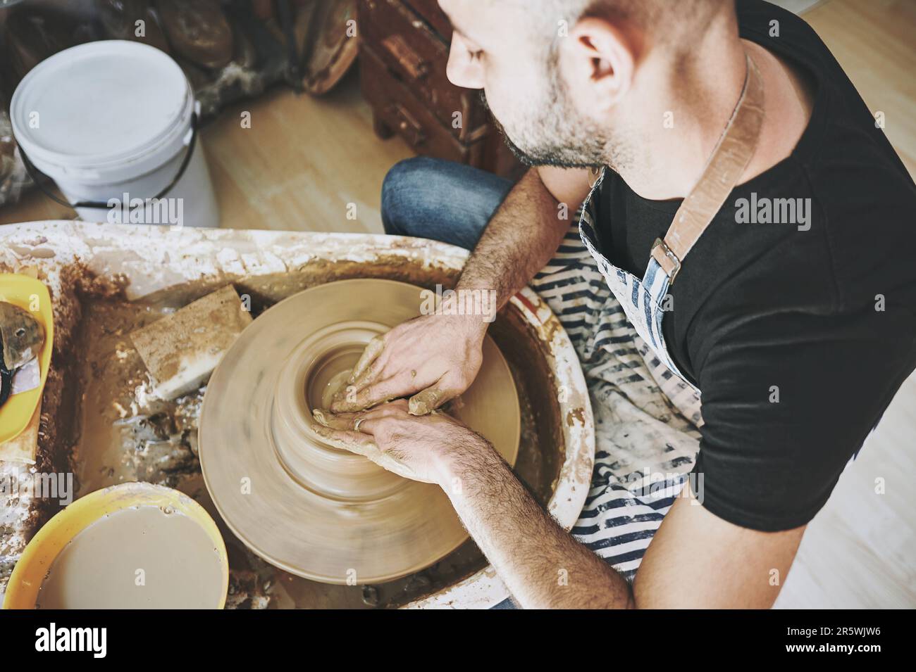 Nourish your heart with art. a young man working with clay in a pottery ...