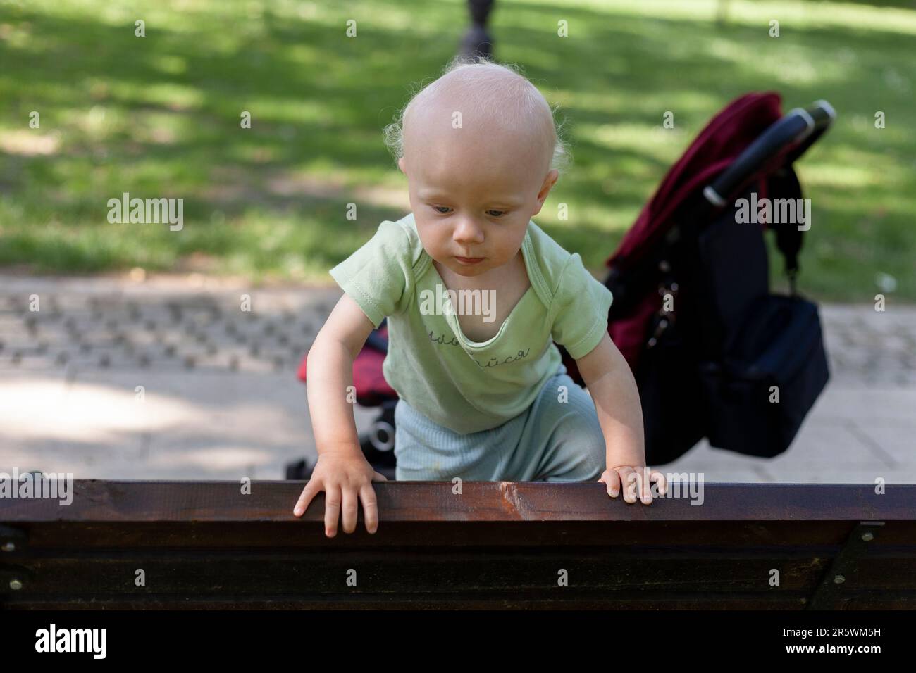 Little blond hair baby boy climbing on a bench in the park Stock Photo ...