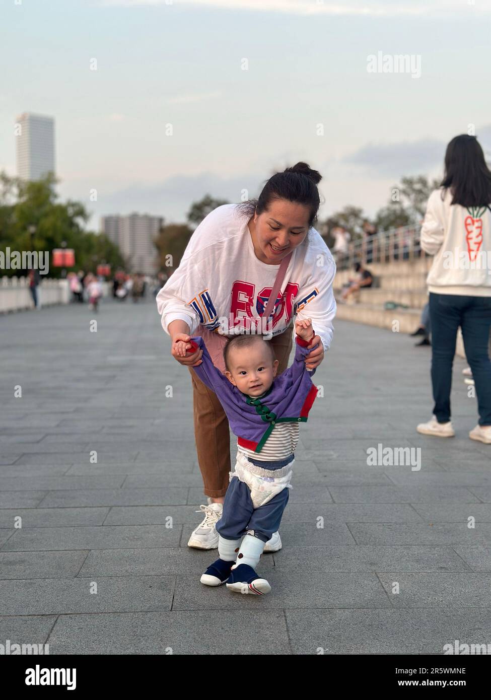 The mother helps her son to stand as he learns to walk Stock Photo - Alamy