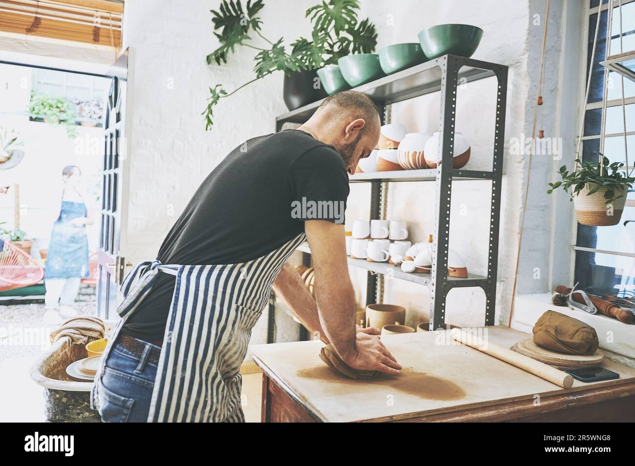 Recycling clay takes a bit of elbow grease. a young man kneading clay ...