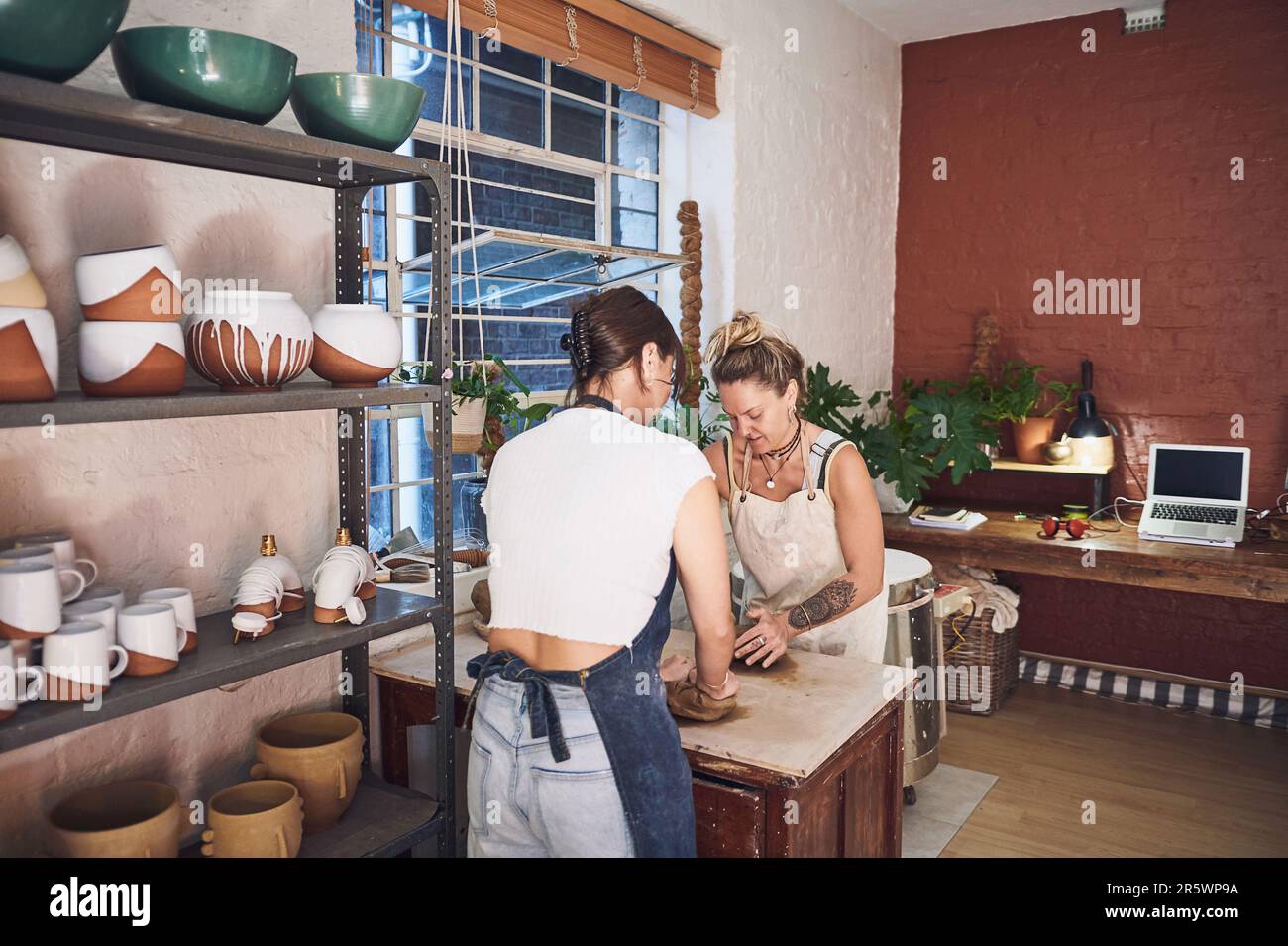 Practice makes perfect pottery. two young women kneading clay in a ...