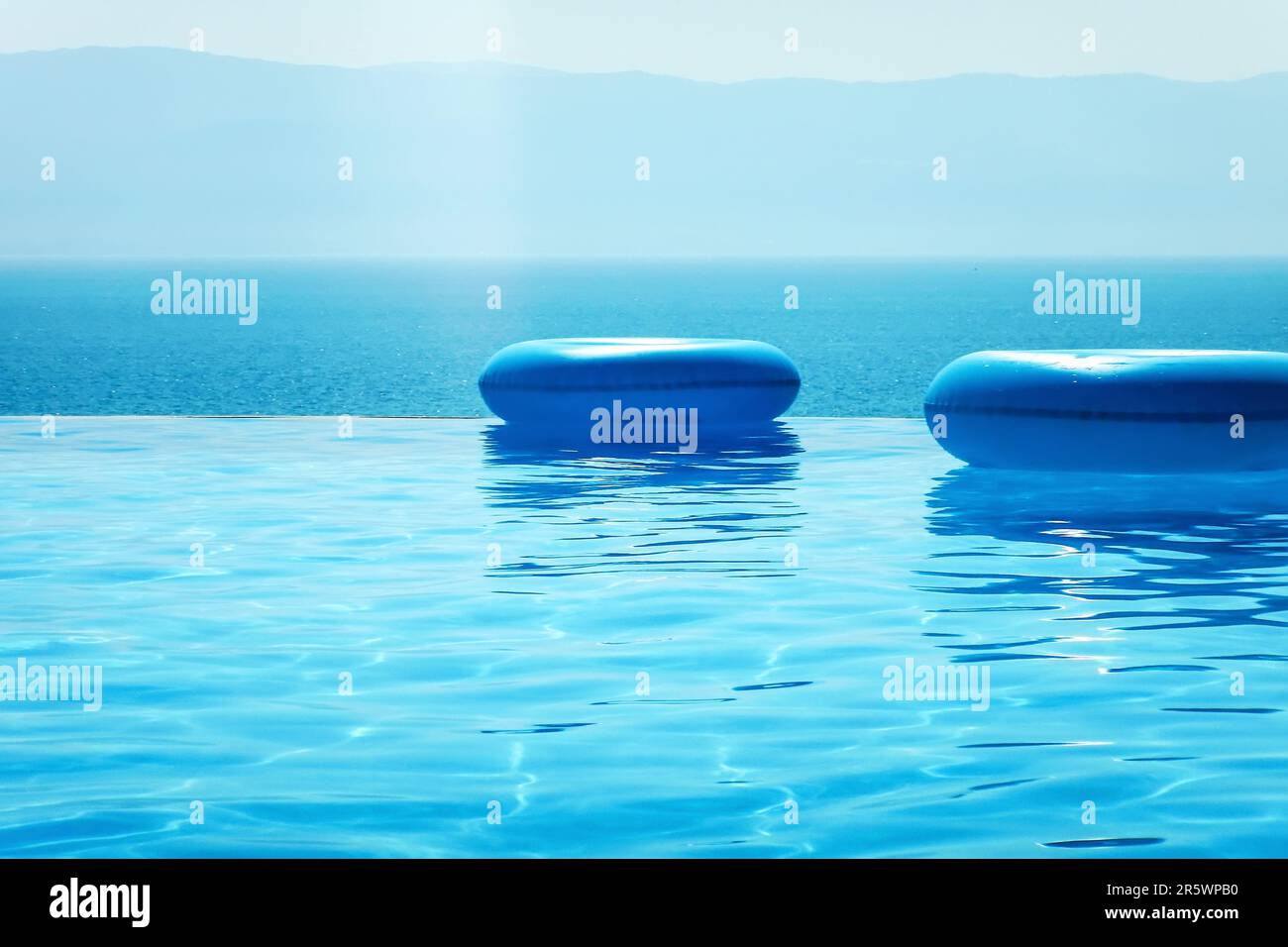 Infinity swimming pool with sea and Mountain View, blue float Stock ...