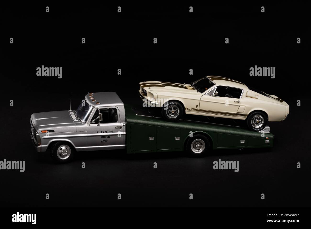 A close-up shot of two cars on a tow truck against a dark background ...