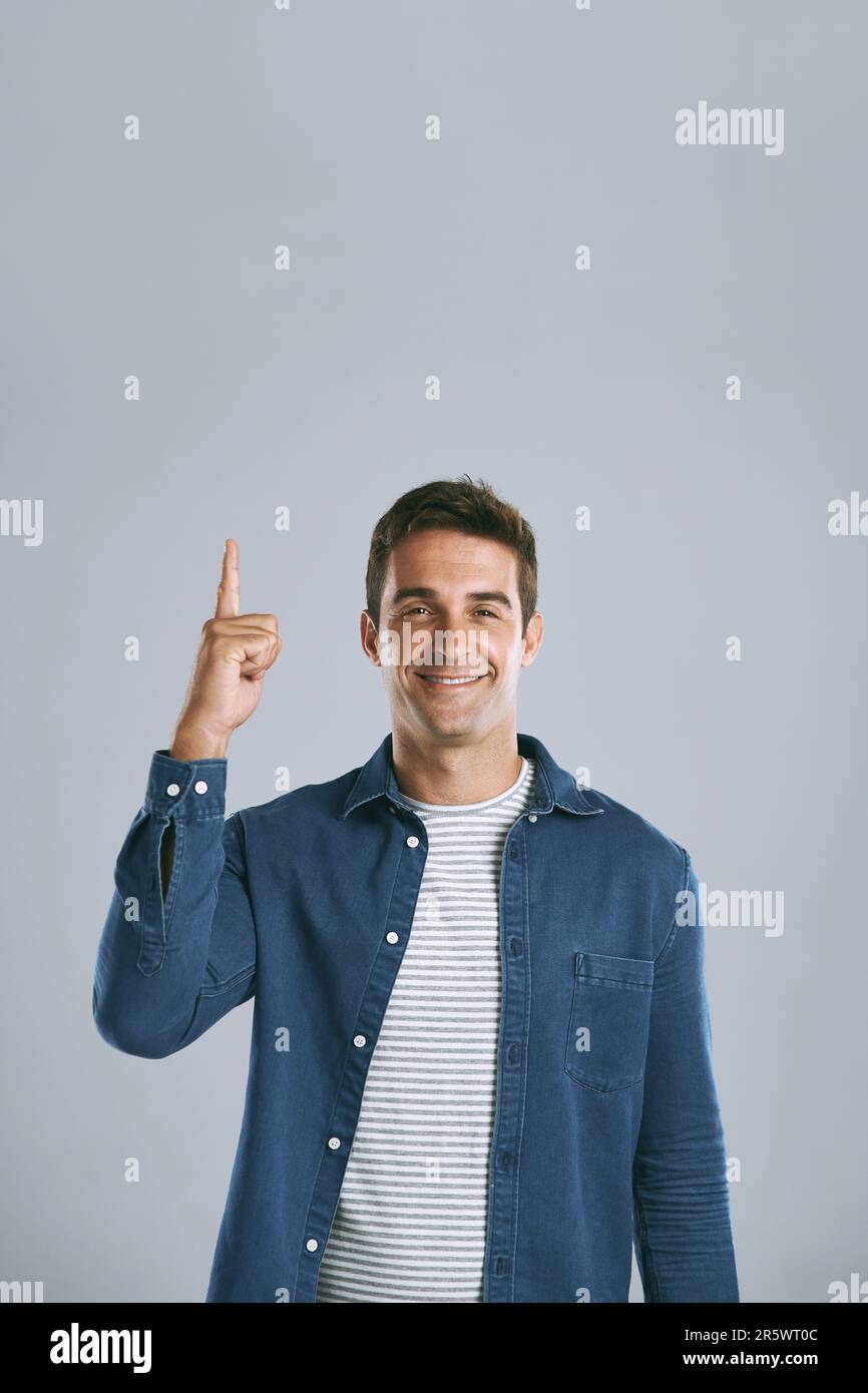 Just look up. a man pointing up against a grey background Stock Photo ...