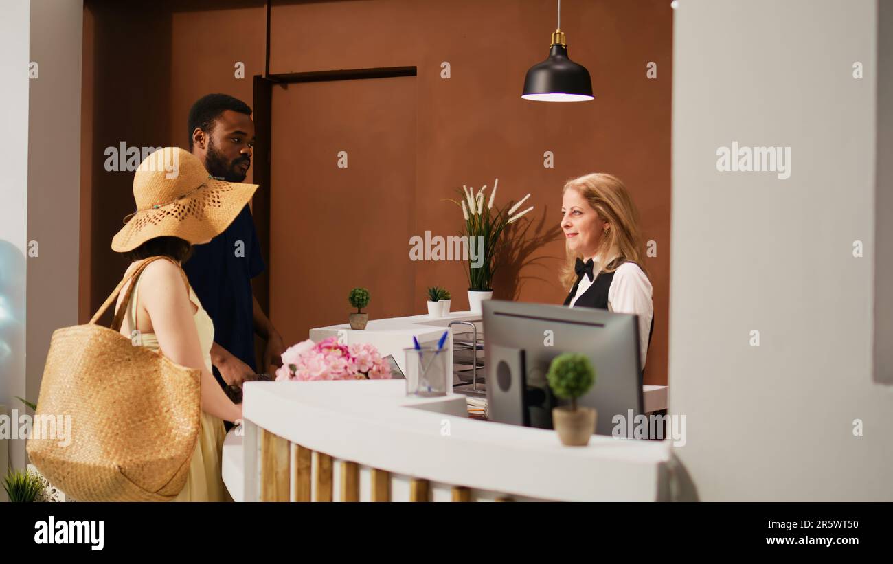 Hotel staff welcoming guests at front desk, preparing to register on ...