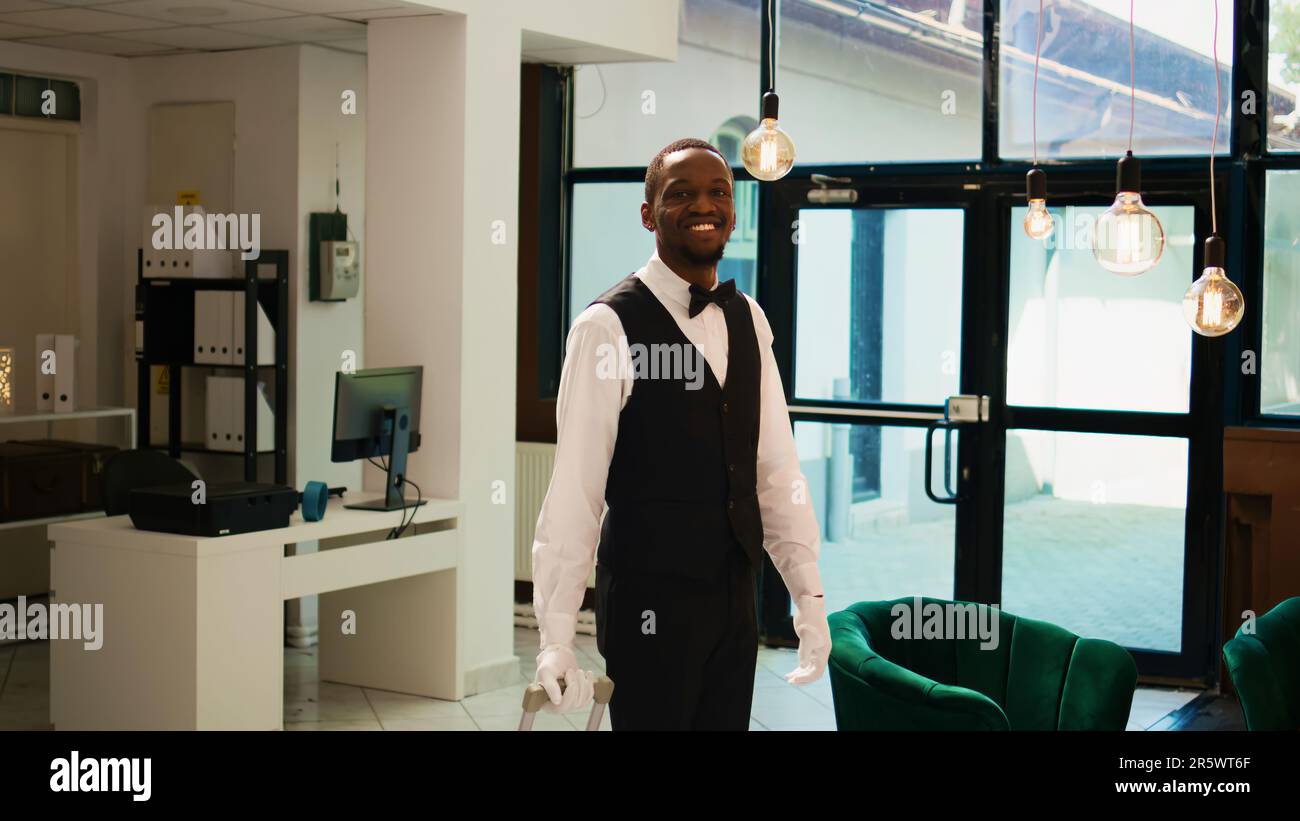 Hotel bellhop carrying lugagge in lobby, providing luxury service to ...