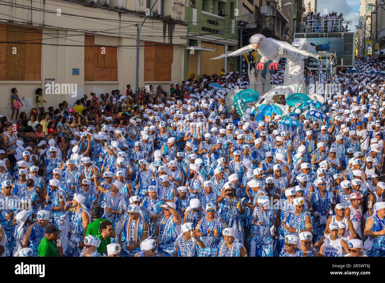 A group of people wearing blue costumes, walking down a street in a ...