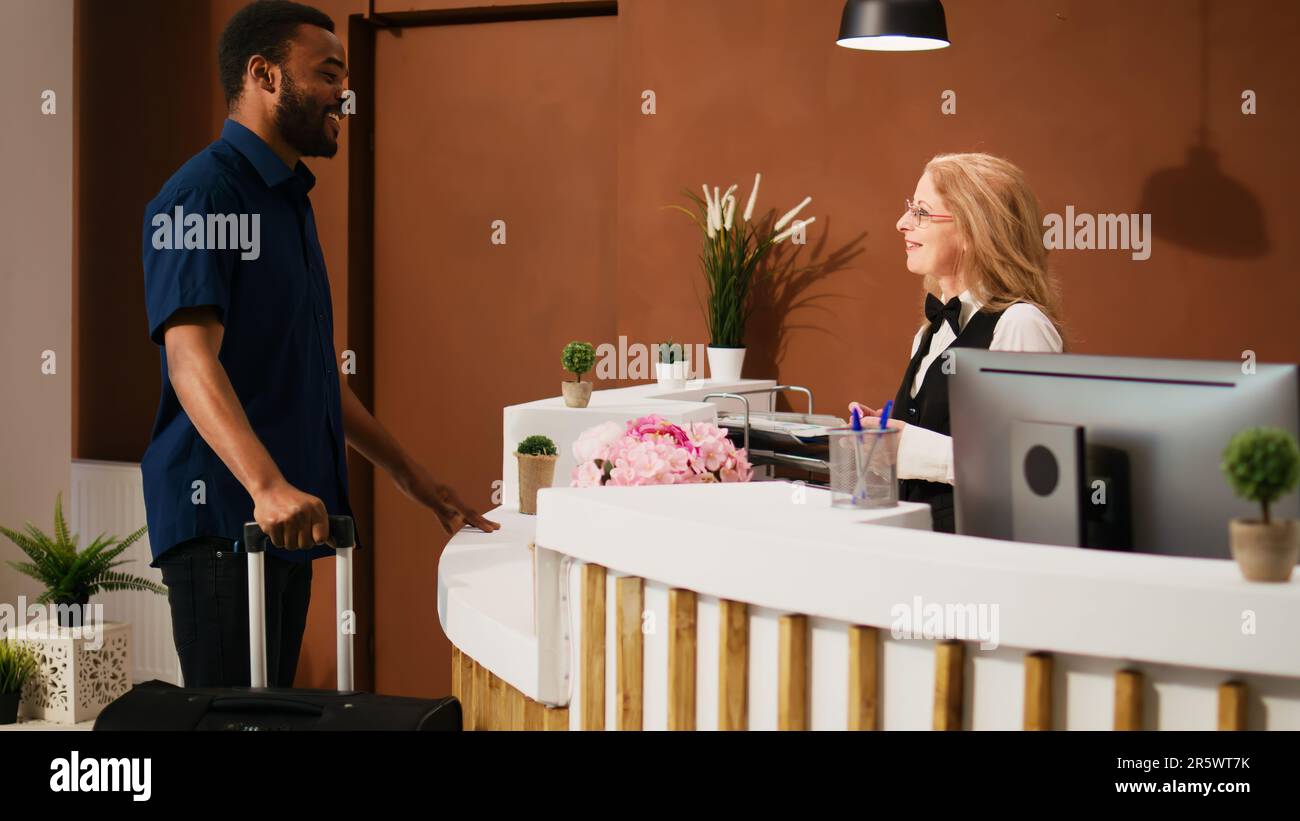 Man tourist carrying baggage in lobby, entering hotel reception with ...