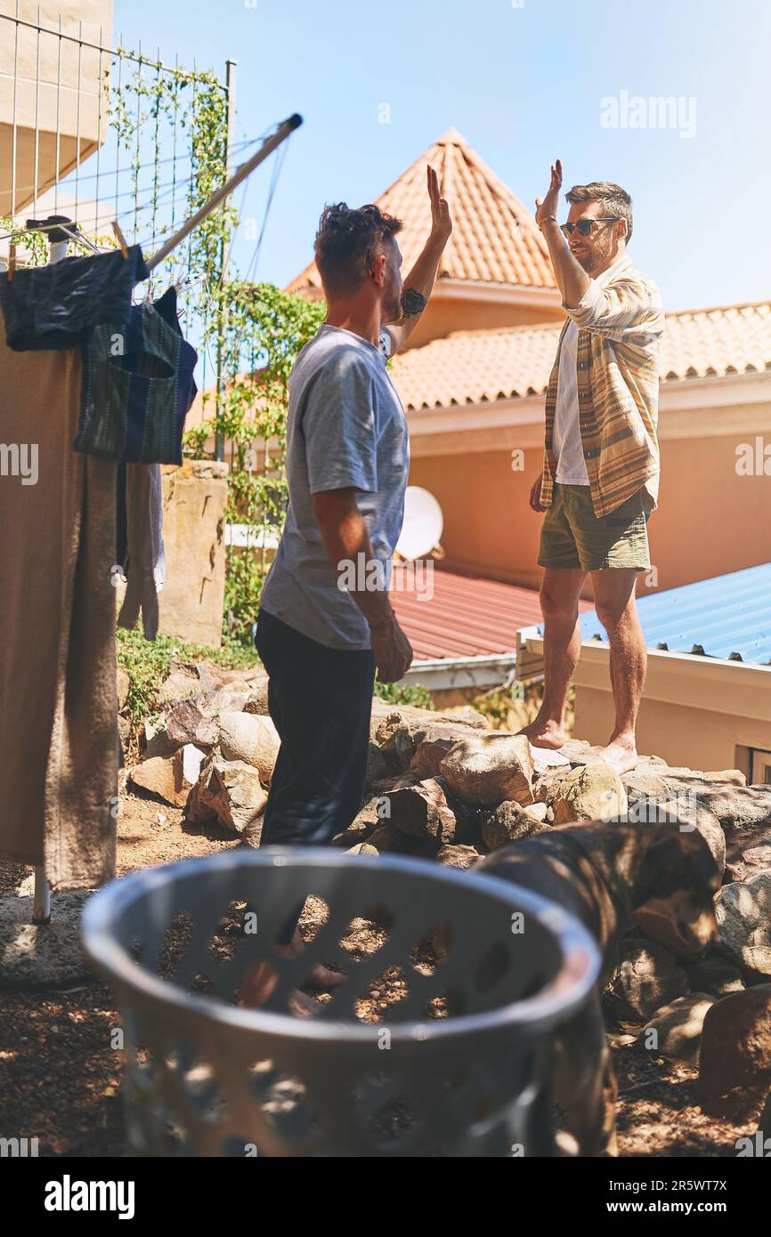 Put them up high partner. High angle shot of two cheerful young men ...