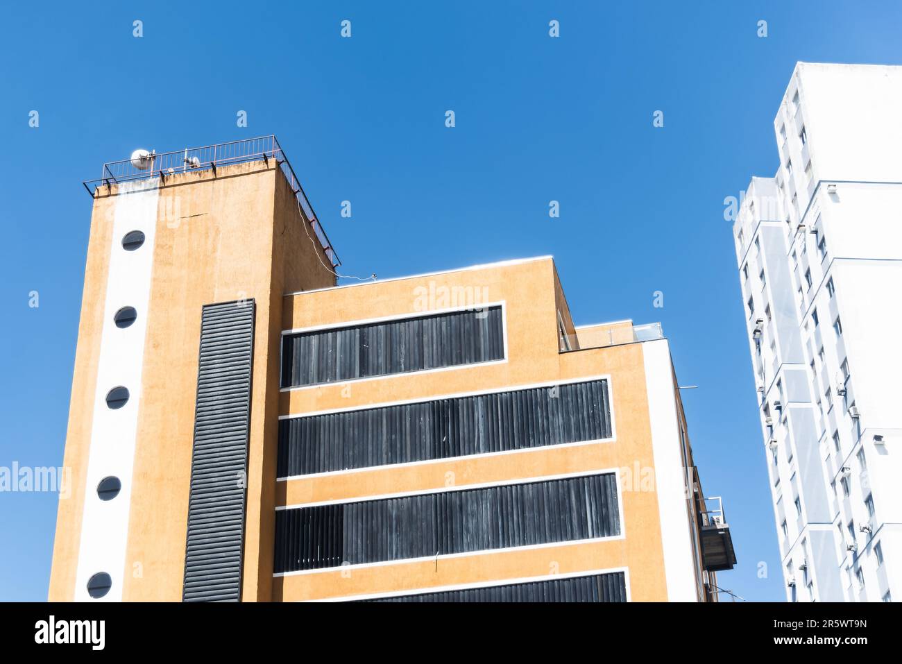 A modern building with large black windows against a beautiful blue sky ...