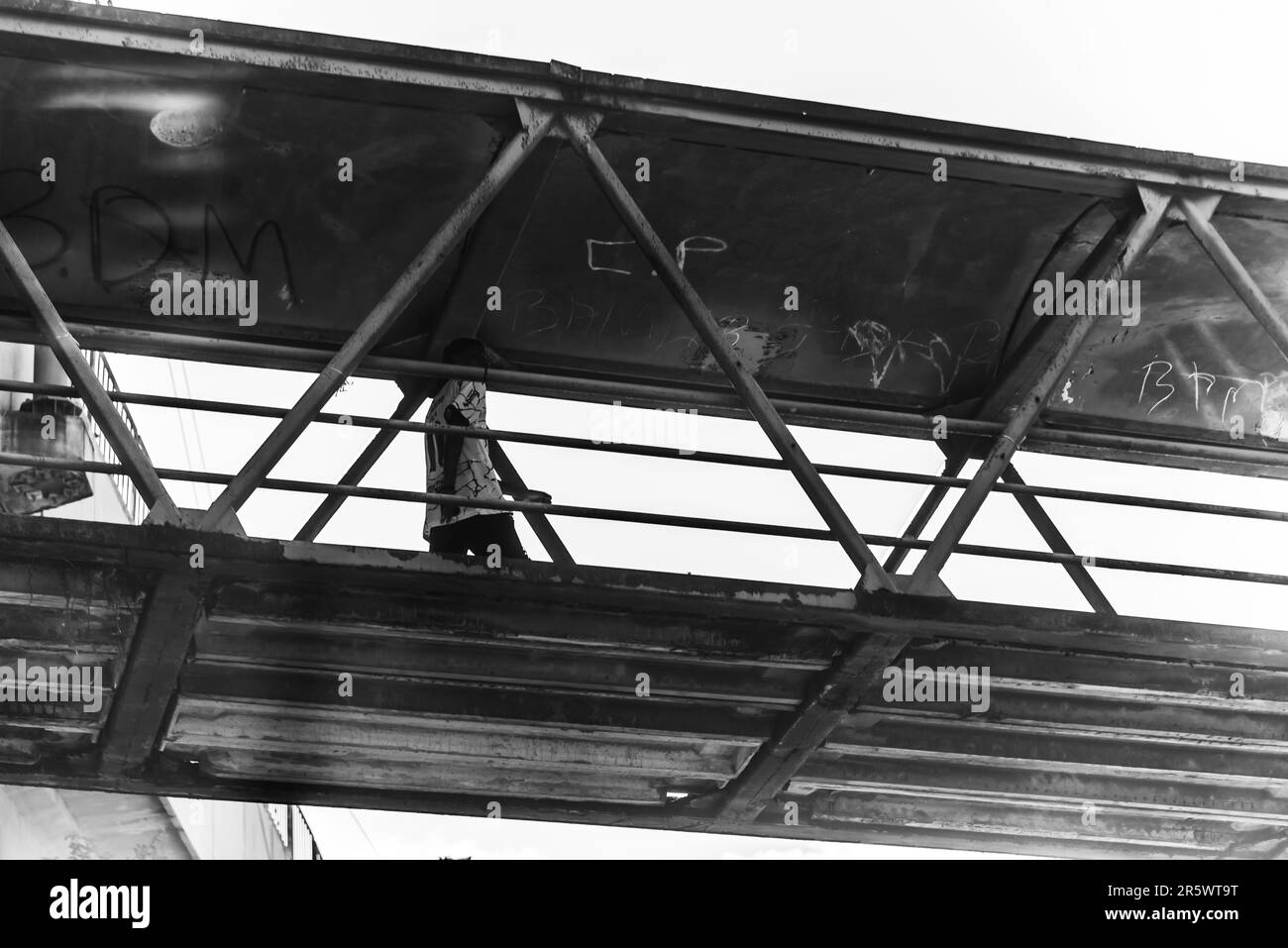 A metal bridge spanning a busy street below, with a brightly colored ...