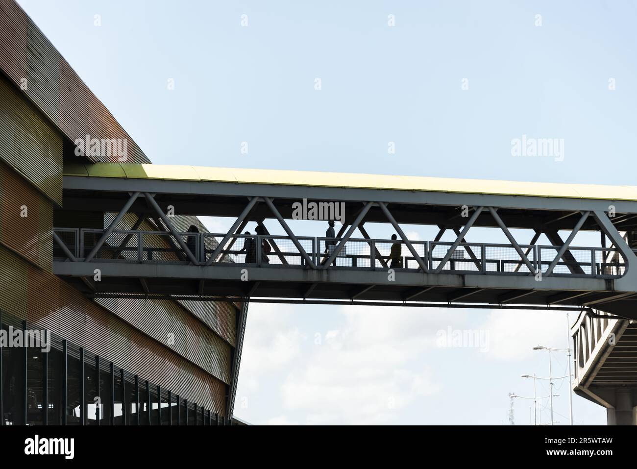 A steel bridge arcs over a busy roadway, with cars and trucks driving ...