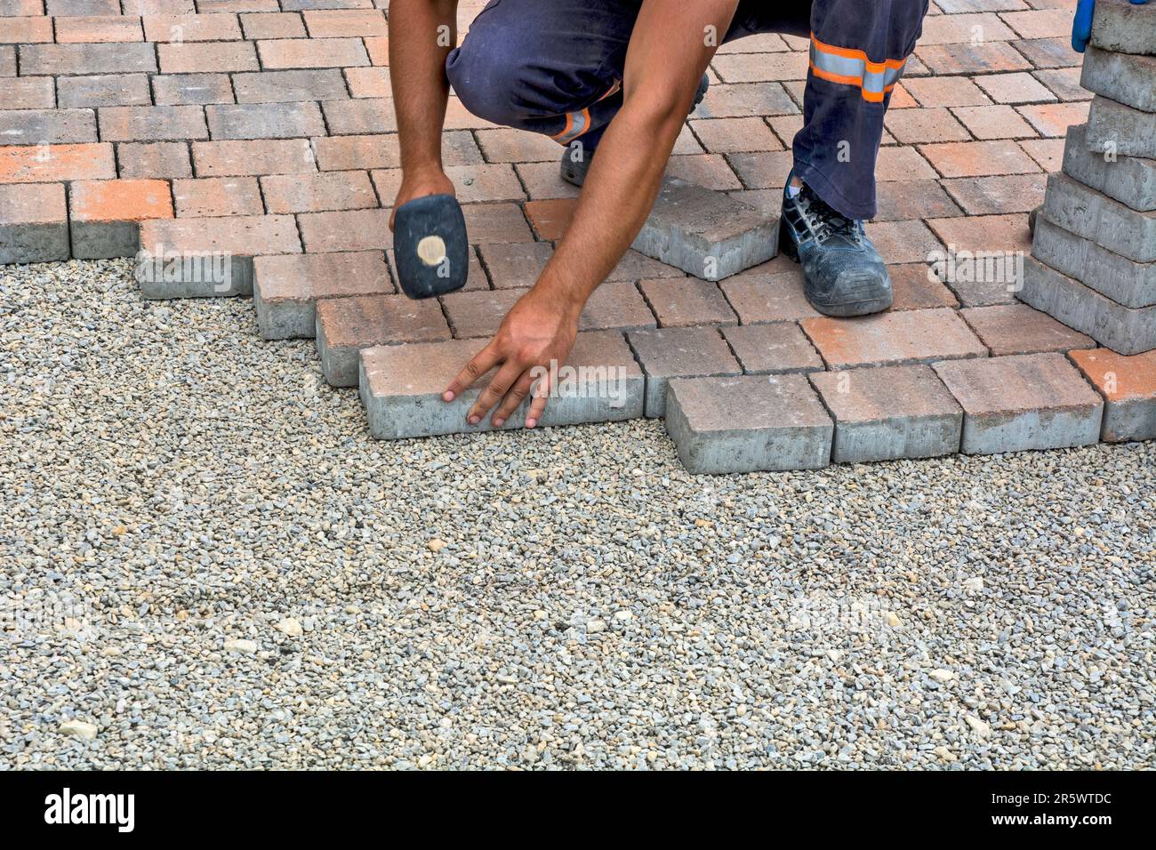 Two construction workers laying down bricks in front of an existing ...
