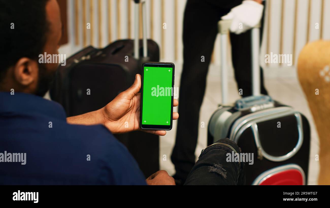 Travellers using greenscreen on phone, sitting in lounge area at hotel ...