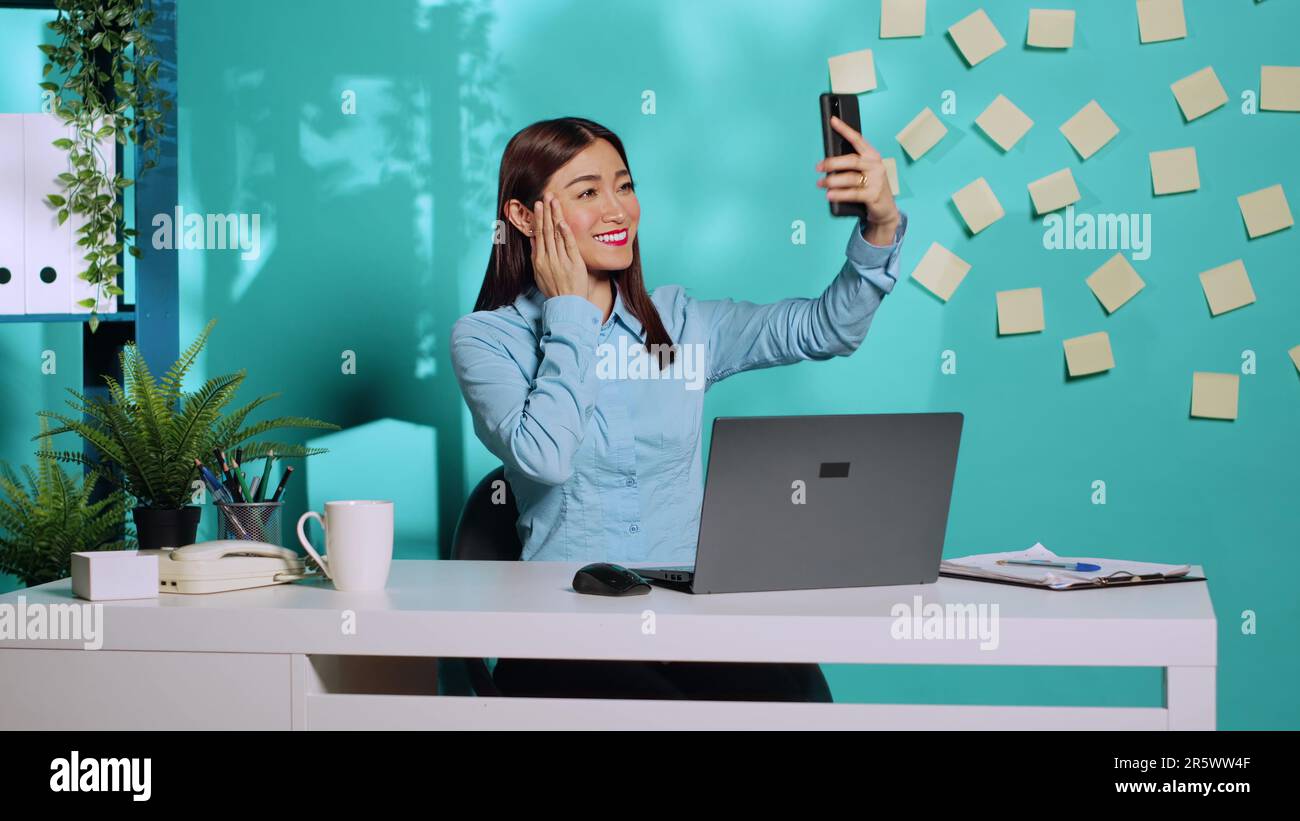 Bubbly joyful employee taking photo selfies with smartphone, throwing ...
