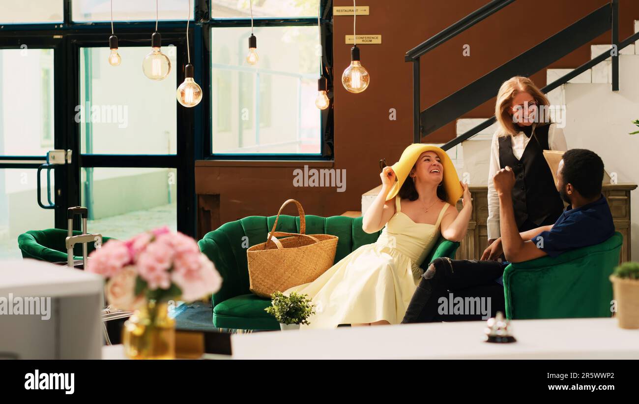 Receptionist providing luxury service to guests sitting in lounge area ...