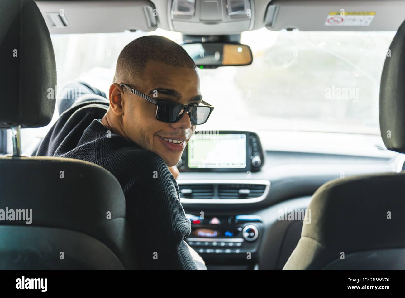 Black male in car driving seat turning back - Interior view od luxury ...