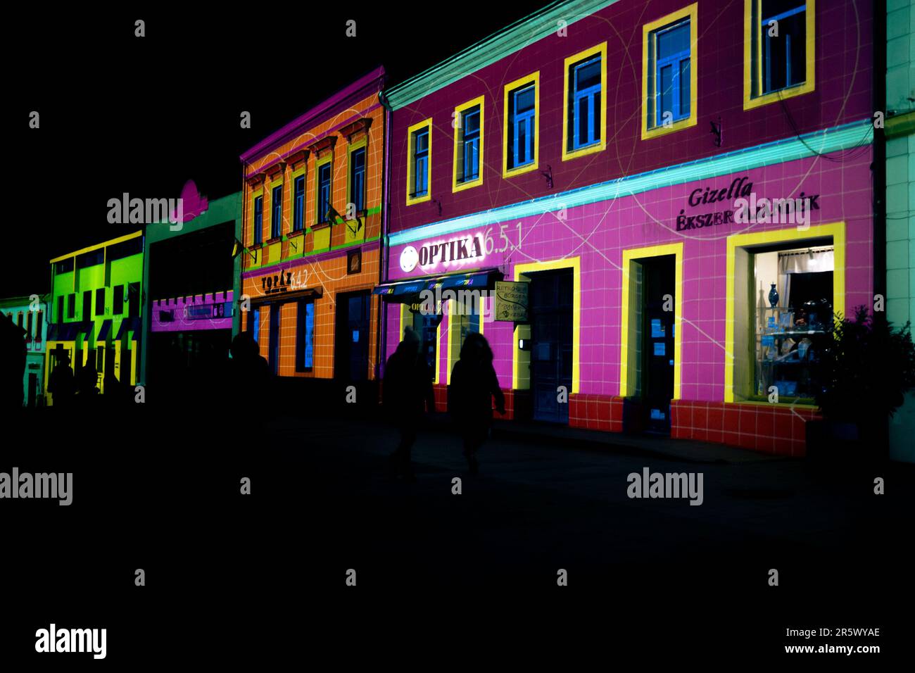 Group of diverse people standing in the evening outside of a brightly ...