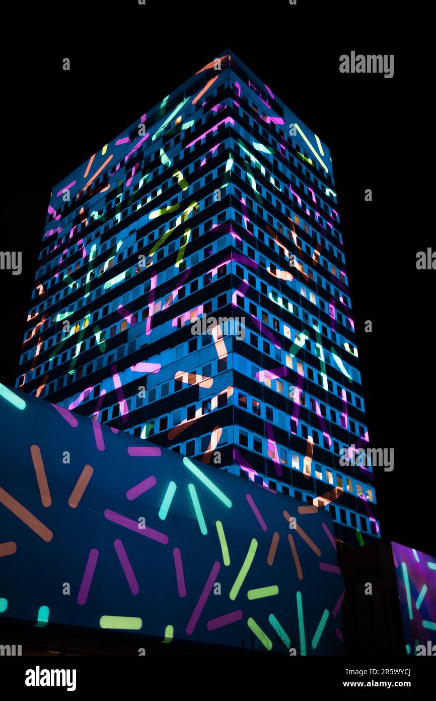 An illuminated high-rise building at night, with a row of bright lights ...