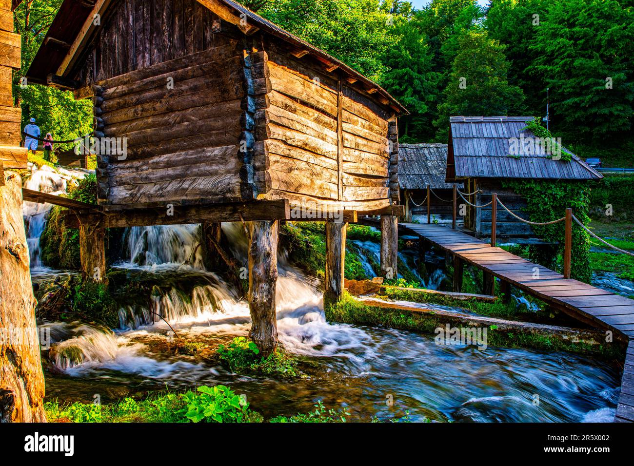 A rustic wooden house with a tranquil stream flowing beneath it ...