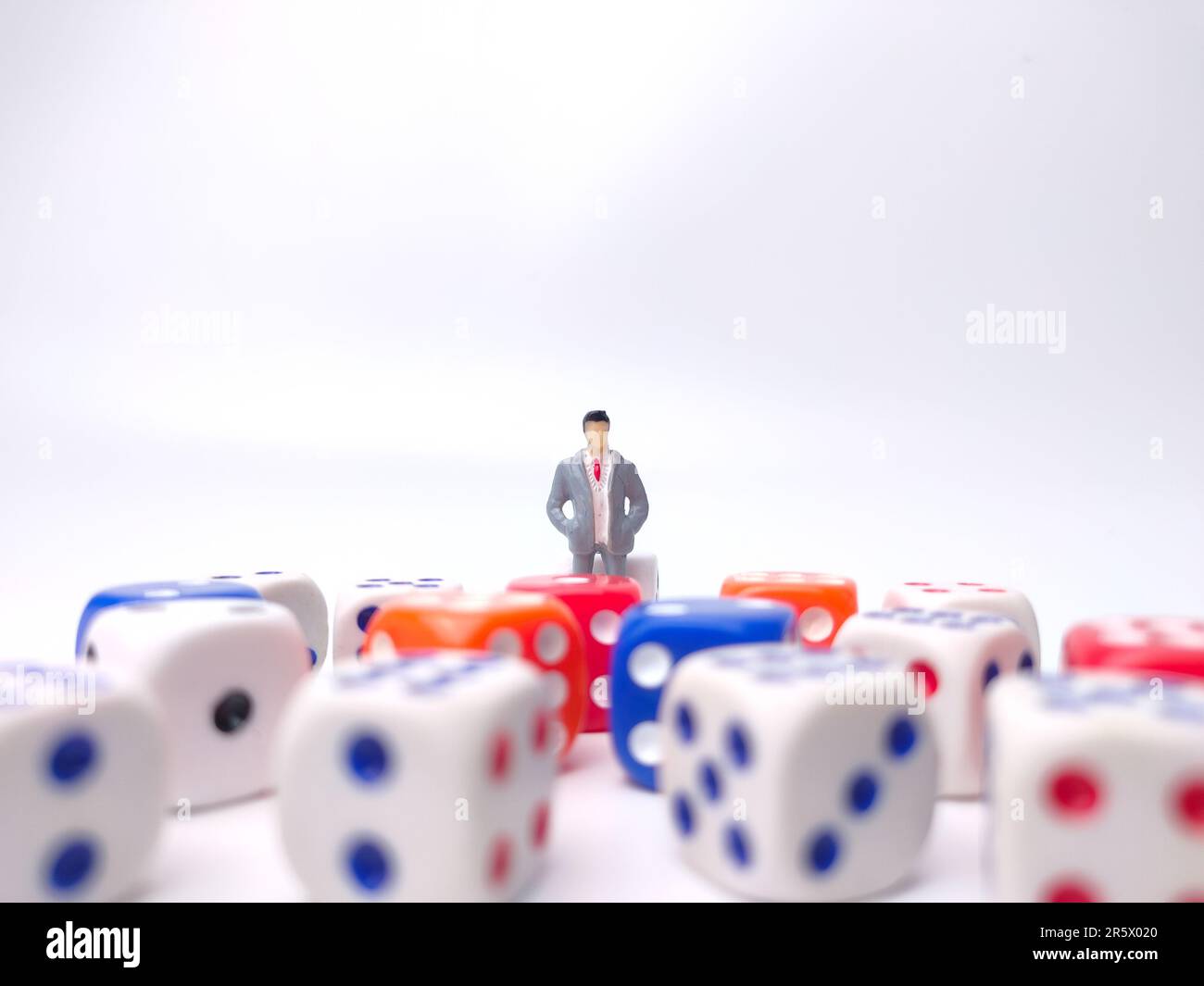 A human figurine is surrounded by a vibrant array of colorful dice ...