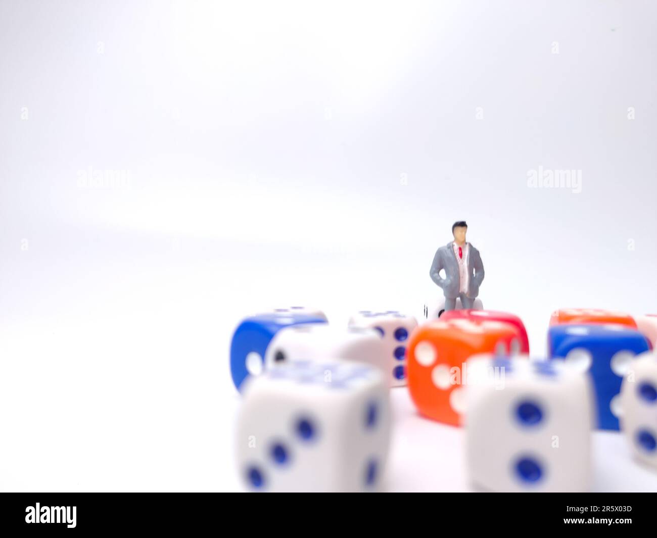 A human figurine is surrounded by a vibrant array of colorful dice ...