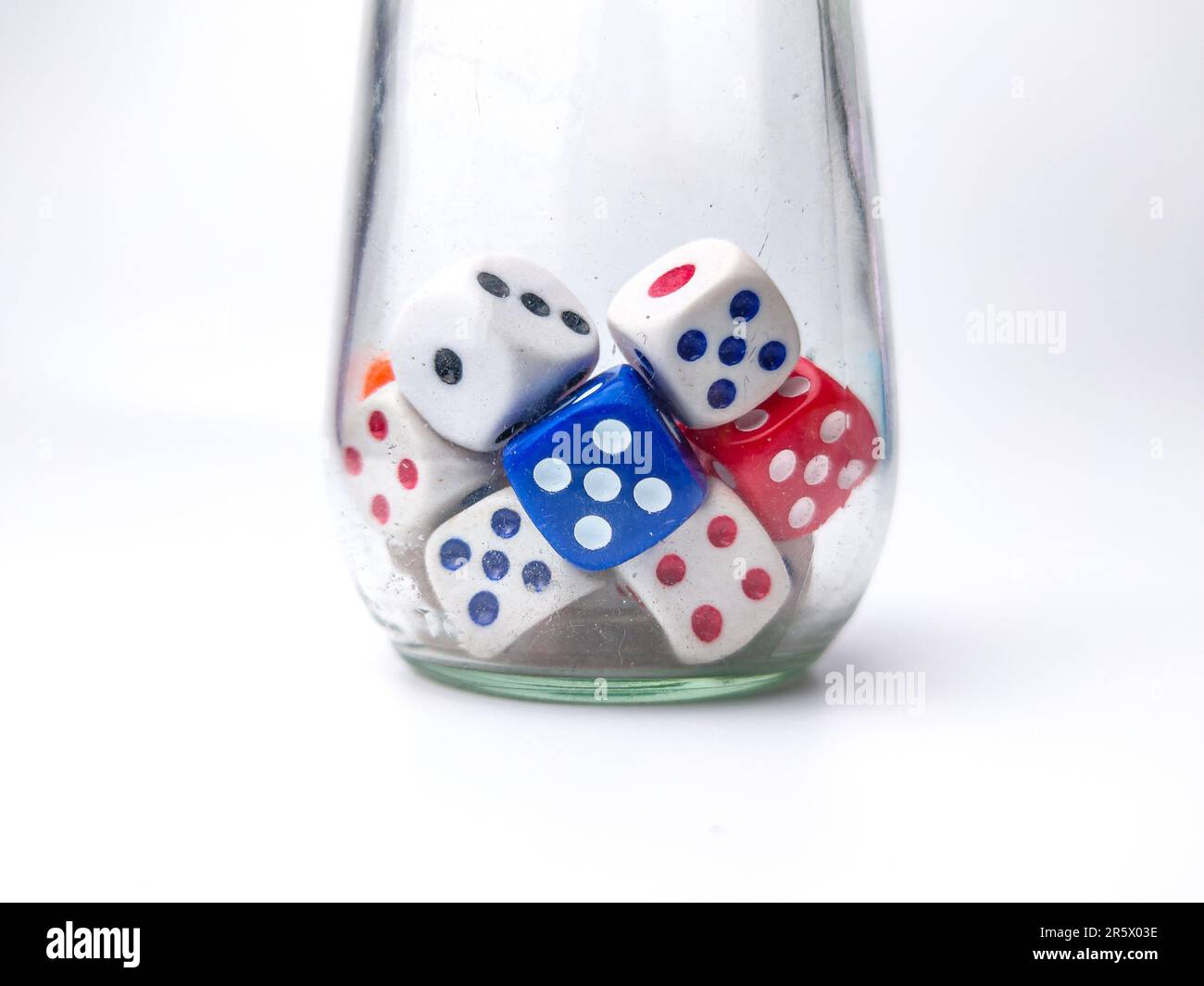 A still life of a glass cup containing multiple dice, lit from the ...