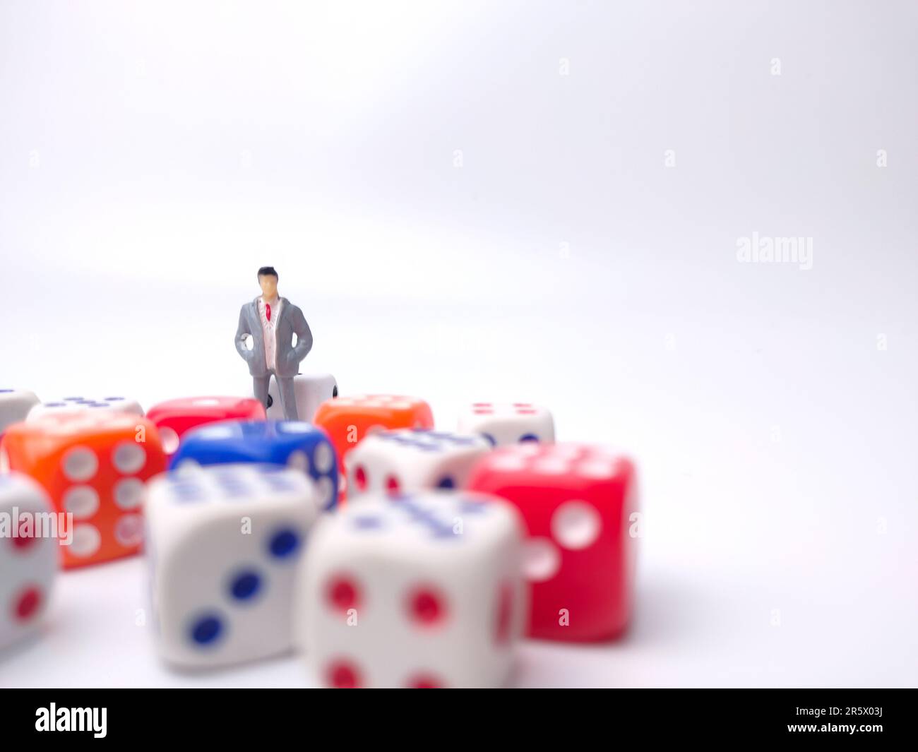 A human figurine is surrounded by a vibrant array of colorful dice ...