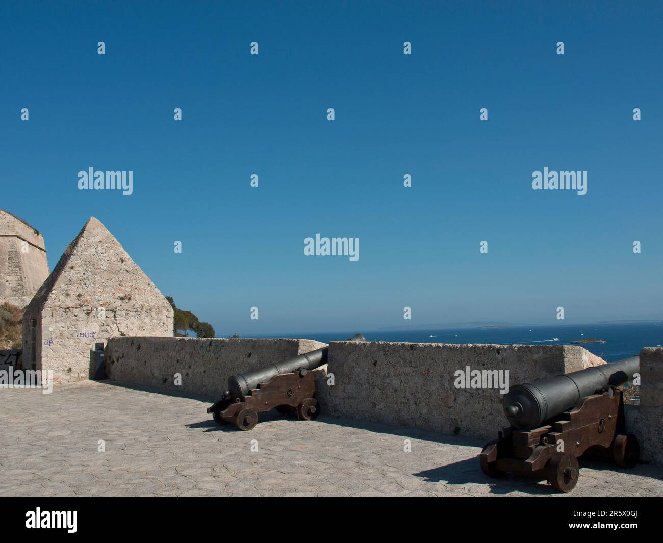 Two antique cannons positioned on the side of a historic stone building ...
