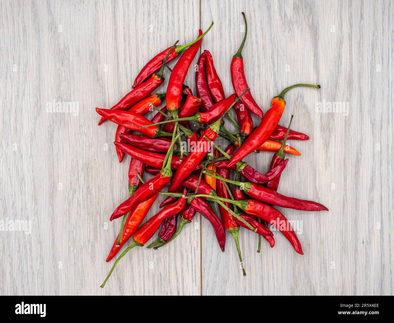 A top view of chili fruits in red and orange colors on a wooden ...