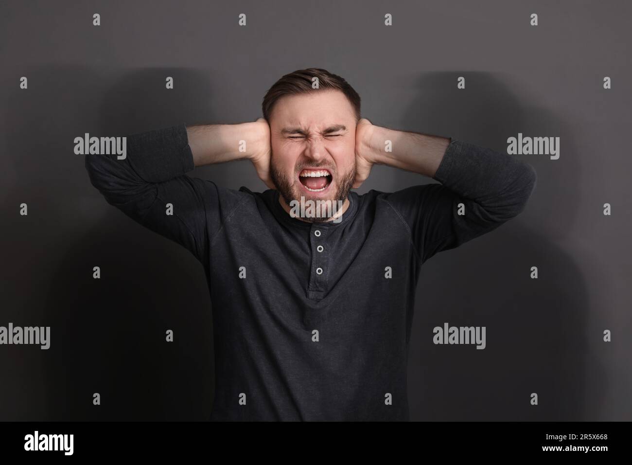 Suffering from hallucination. Man screaming and closing ears not to ...