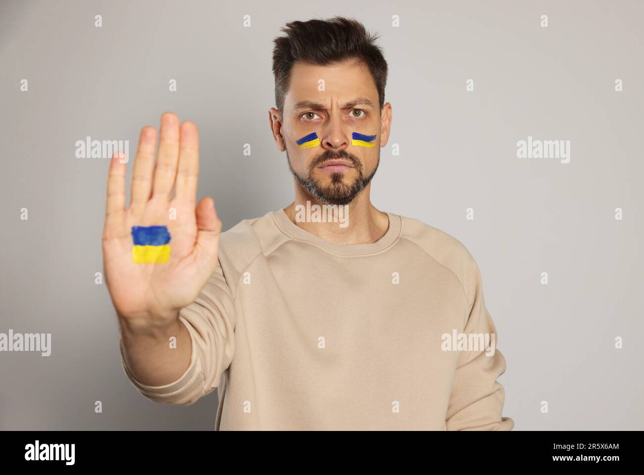 Angry man with drawings of Ukrainian flag on face and palm against ...