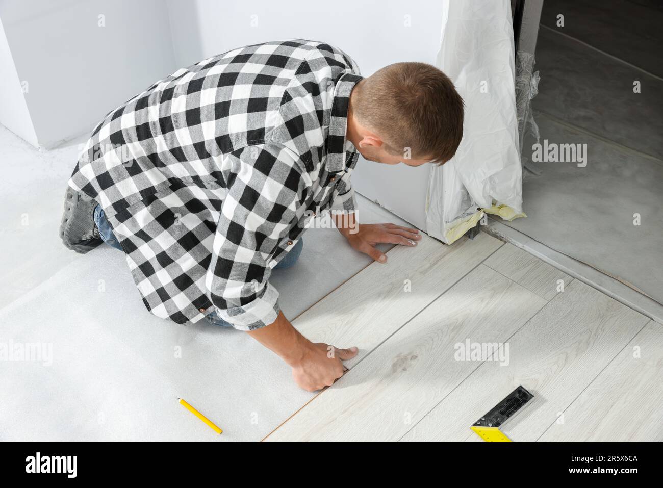 Professional worker installing new laminate flooring indoors Stock Photo - Alamy