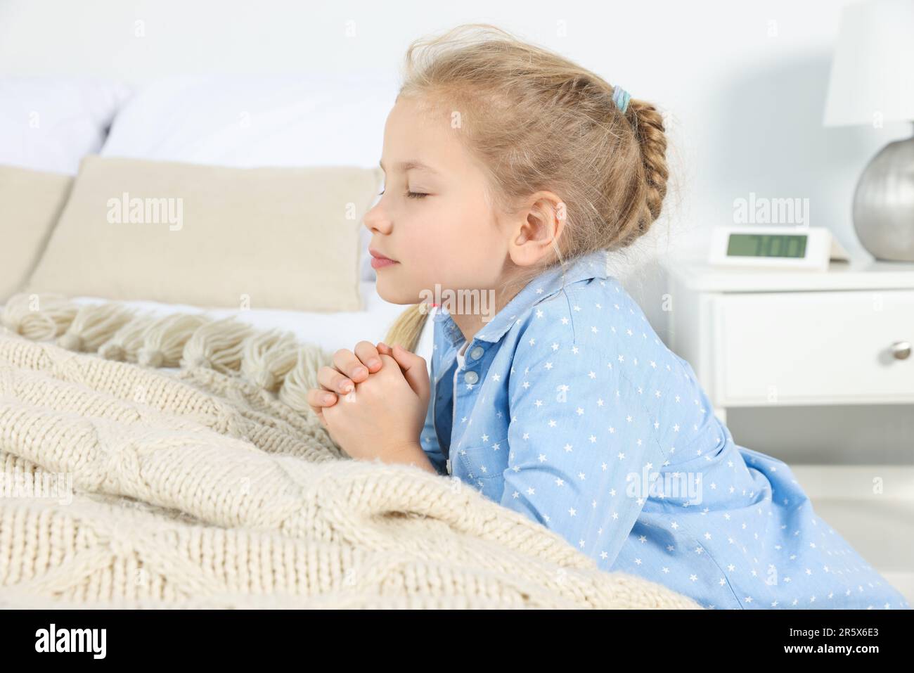 Girl with clasped hands praying near bed at home Stock Photo - Alamy