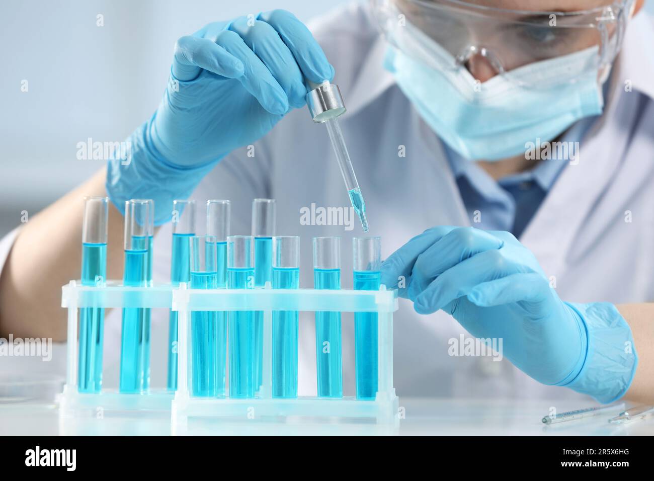 Scientist dripping liquid from pipette into test tube on blurred ...