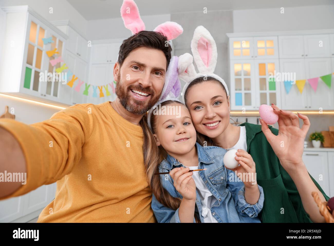 Happy family making selfie while painting Easter eggs in kitchen Stock Photo - Alamy