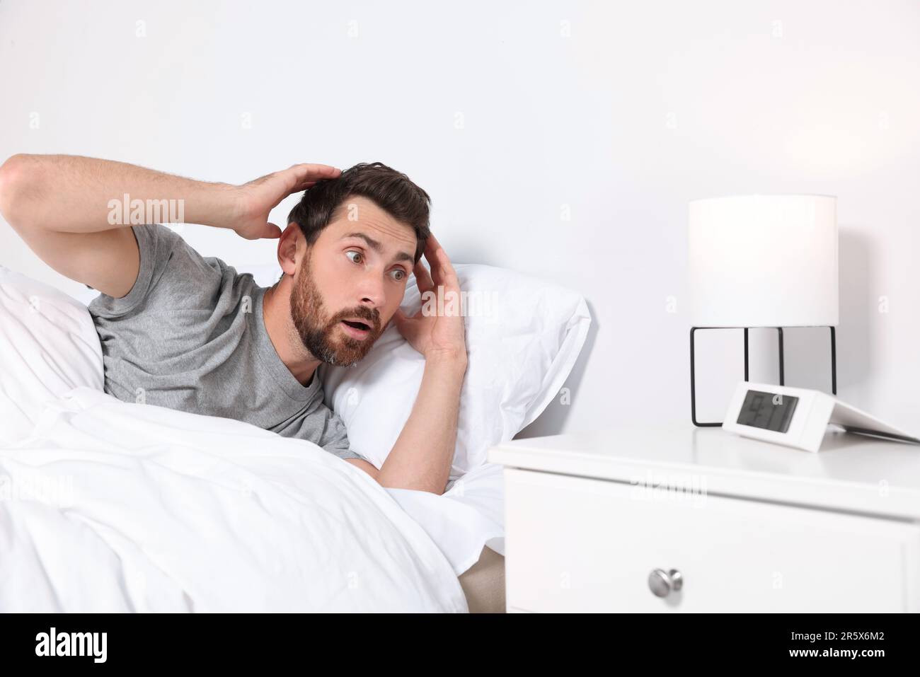 Emotional man in bed at home. Being late because of oversleeping Stock ...