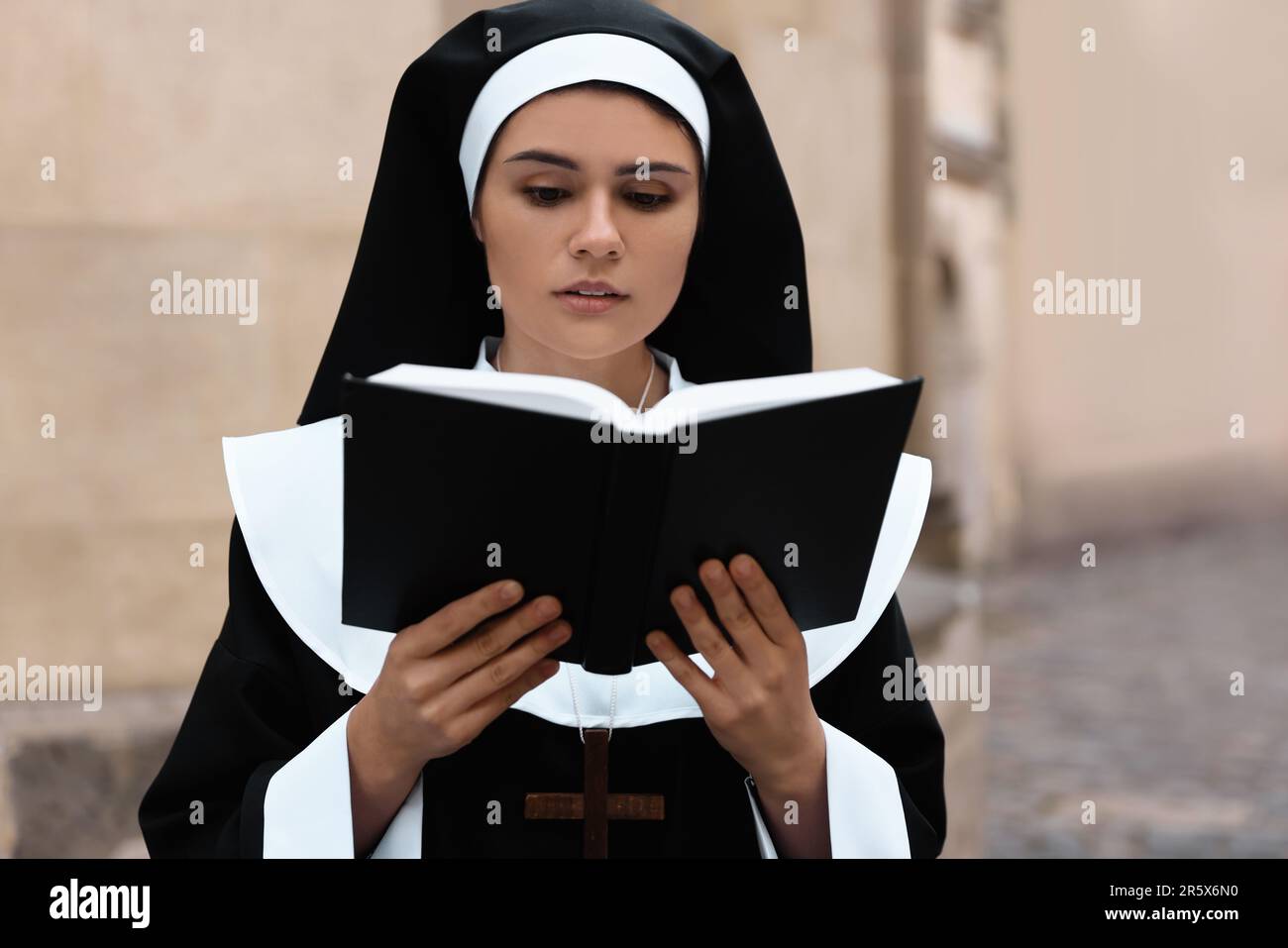 Young nun reading Bible near building outdoors Stock Photo - Alamy