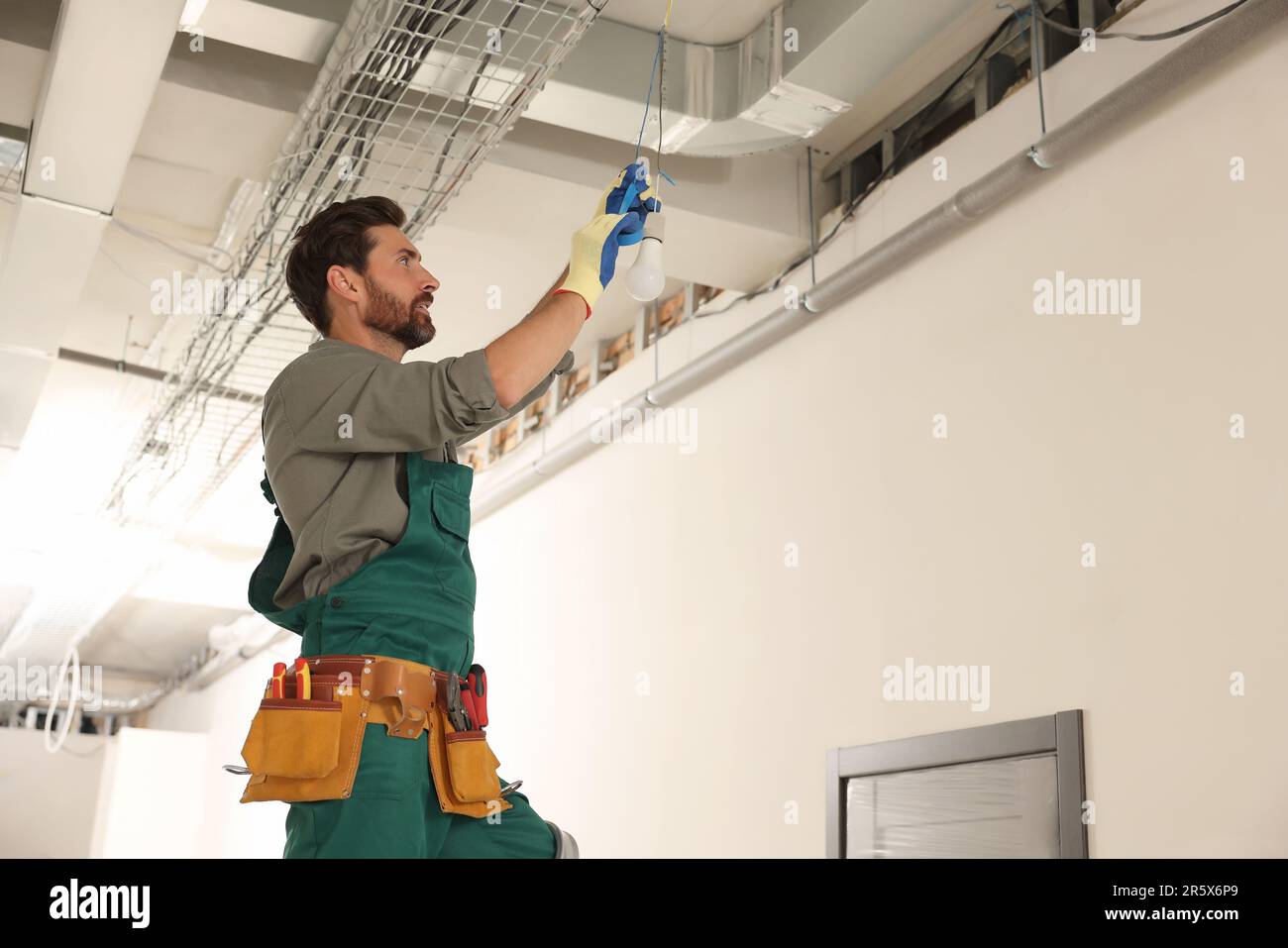 Electrician with insulting tape repairing ceiling lamp Stock Photo - Alamy