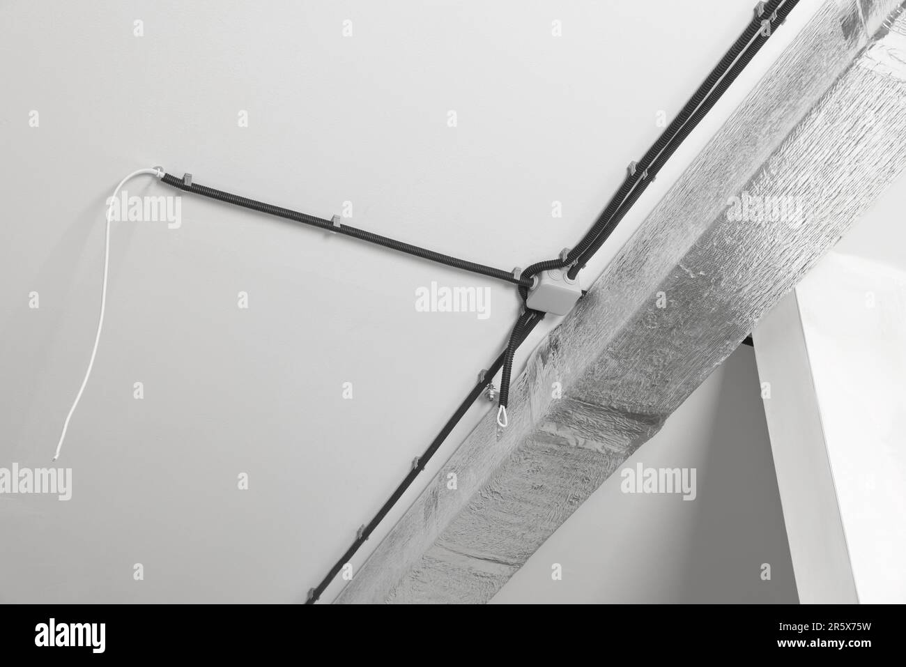 Conduits with cables and ventilation system on white ceiling, low angle ...