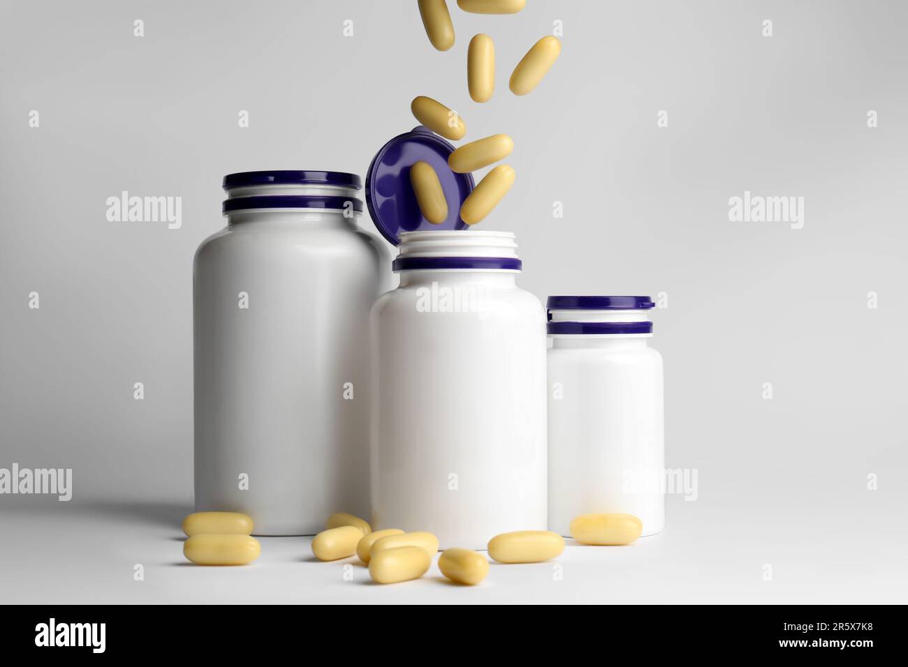 Pills falling into medical bottles on white background Stock Photo - Alamy
