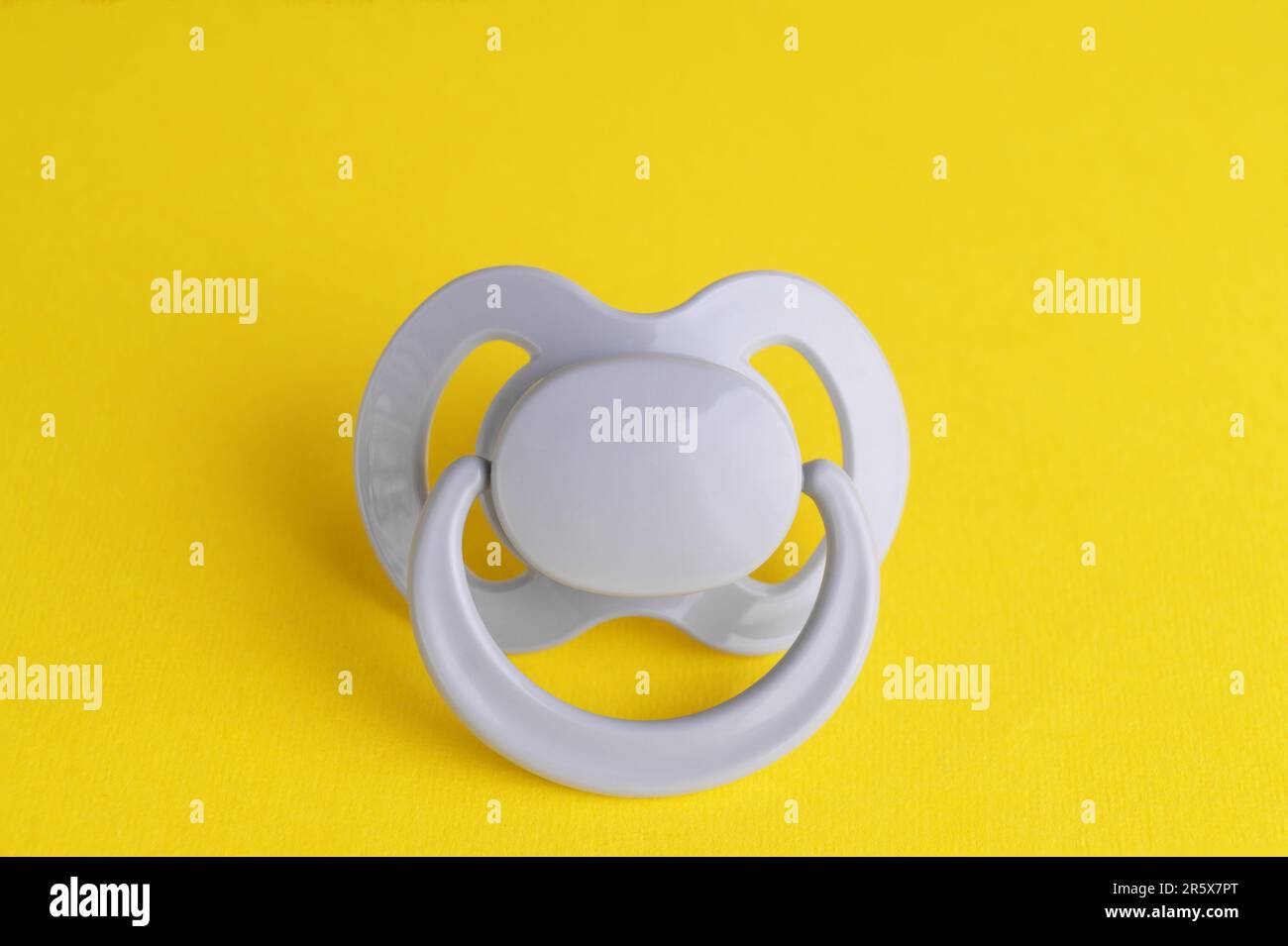 New cute baby pacifier on yellow background Stock Photo - Alamy