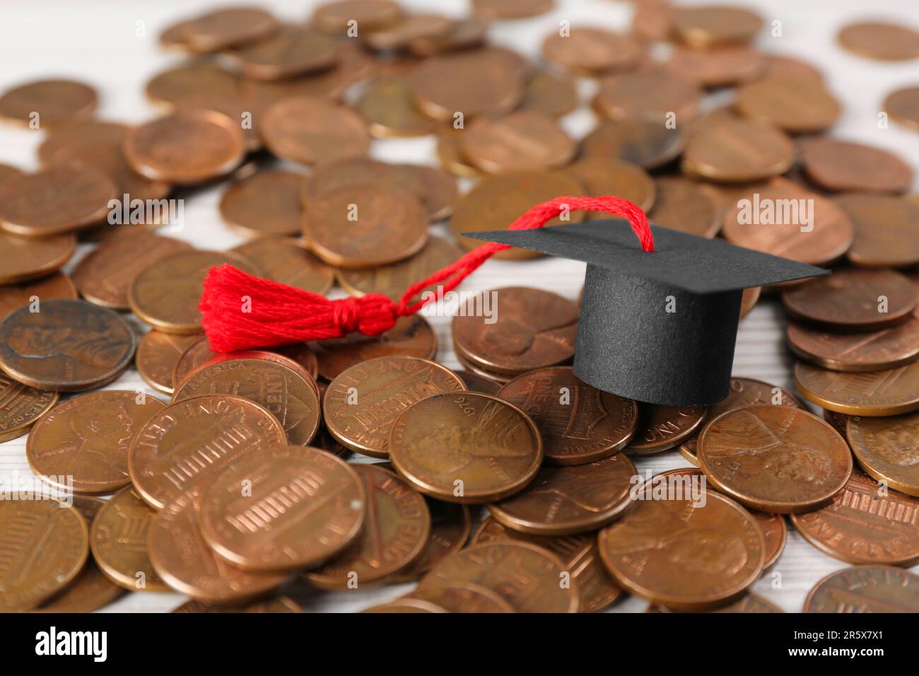 Scholarship concept. Graduation cap and coins on white wooden table ...