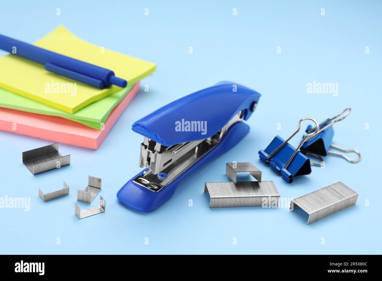 New bright stapler with stationery on light blue background Stock Photo ...